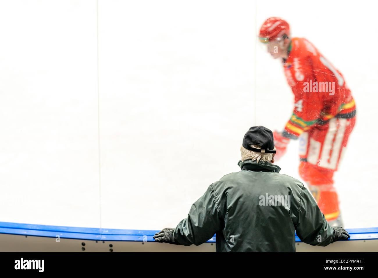 a spectator watches the match through protective glass at the hockey ...