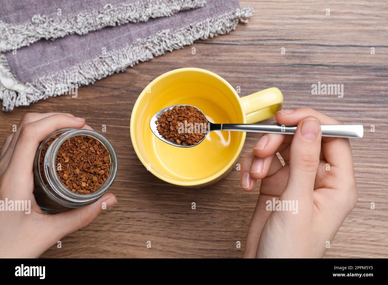 Woman pouring instant coffee into cup at wooden table, top view Stock ...