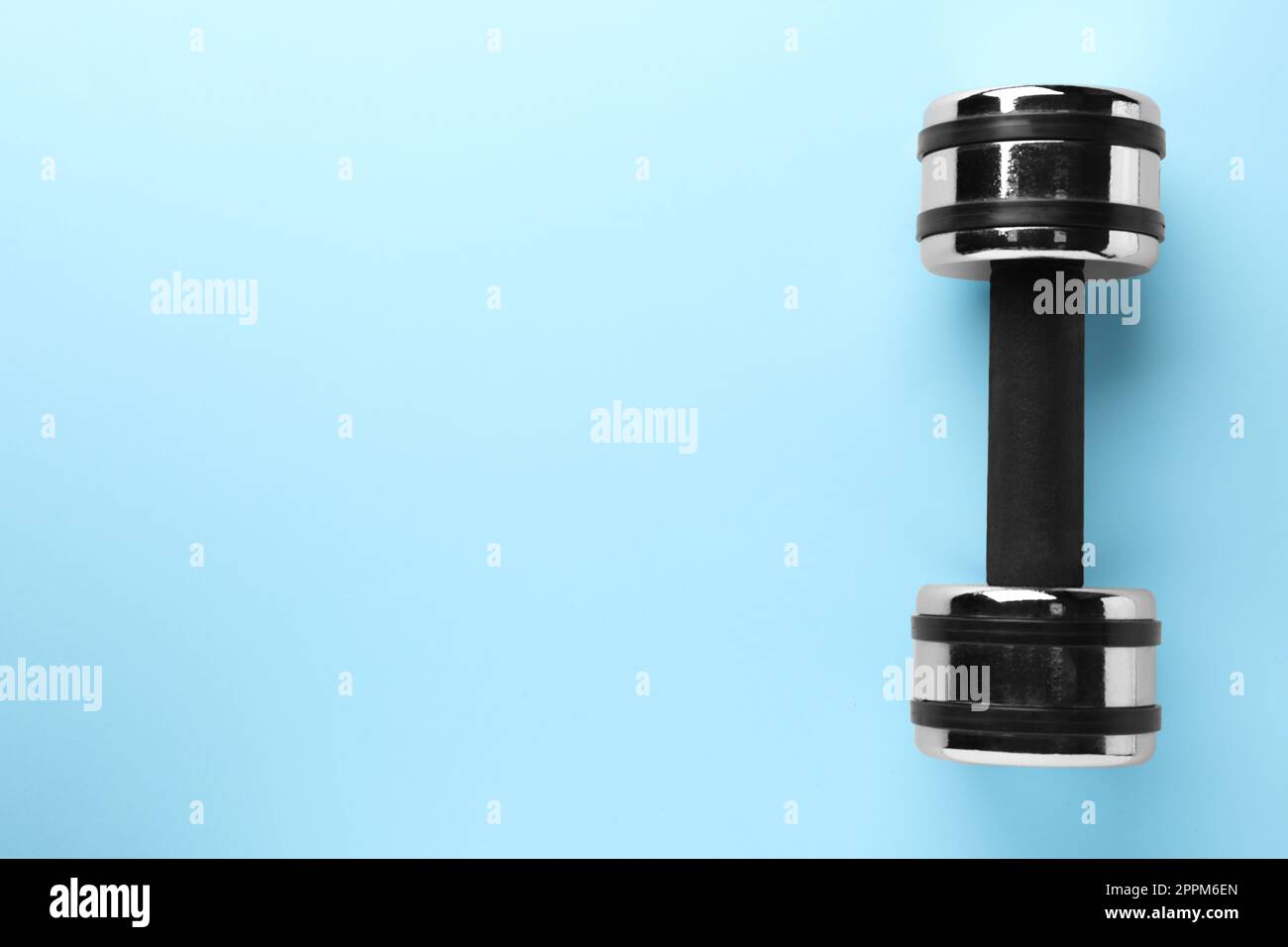 Stylish dumbbell on light blue background, top view. Space for text ...
