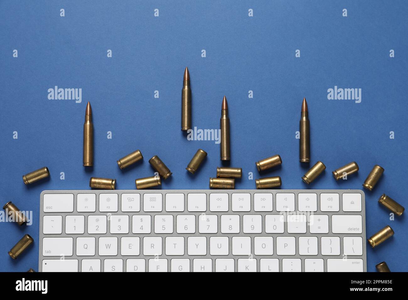 Bullets and computer keyboard on blue background, flat lay. Hybrid ...