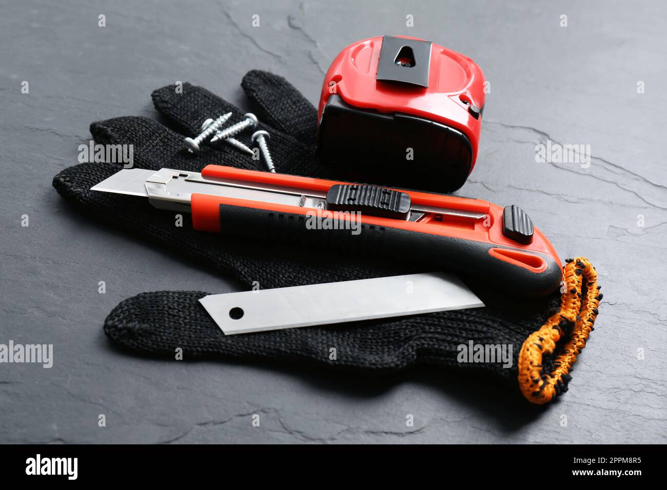 Utility knife, measuring tape and glove on black table, closeup Stock ...
