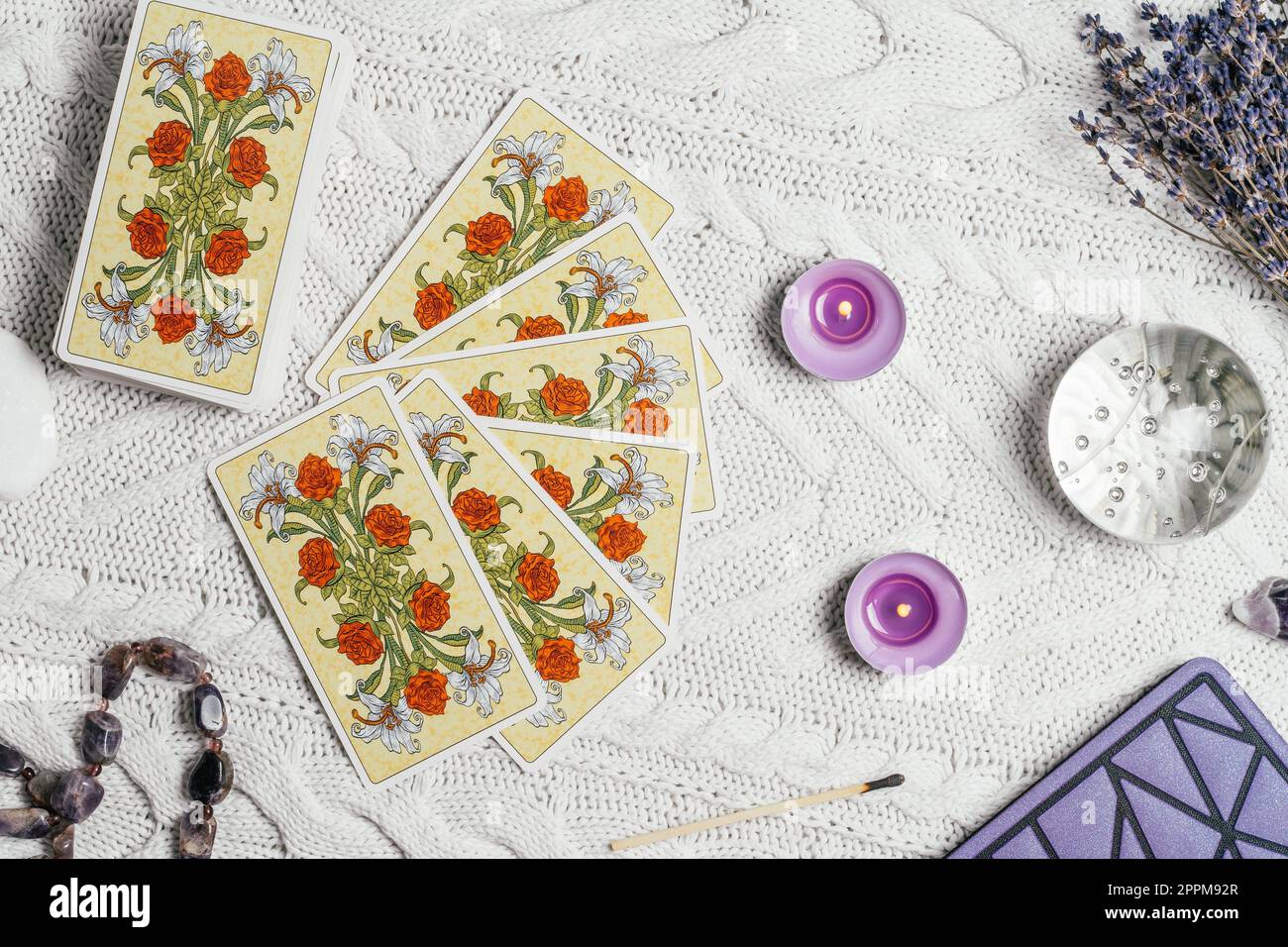 Tarot cards spread face up on white knitted surface with crystal ball ...