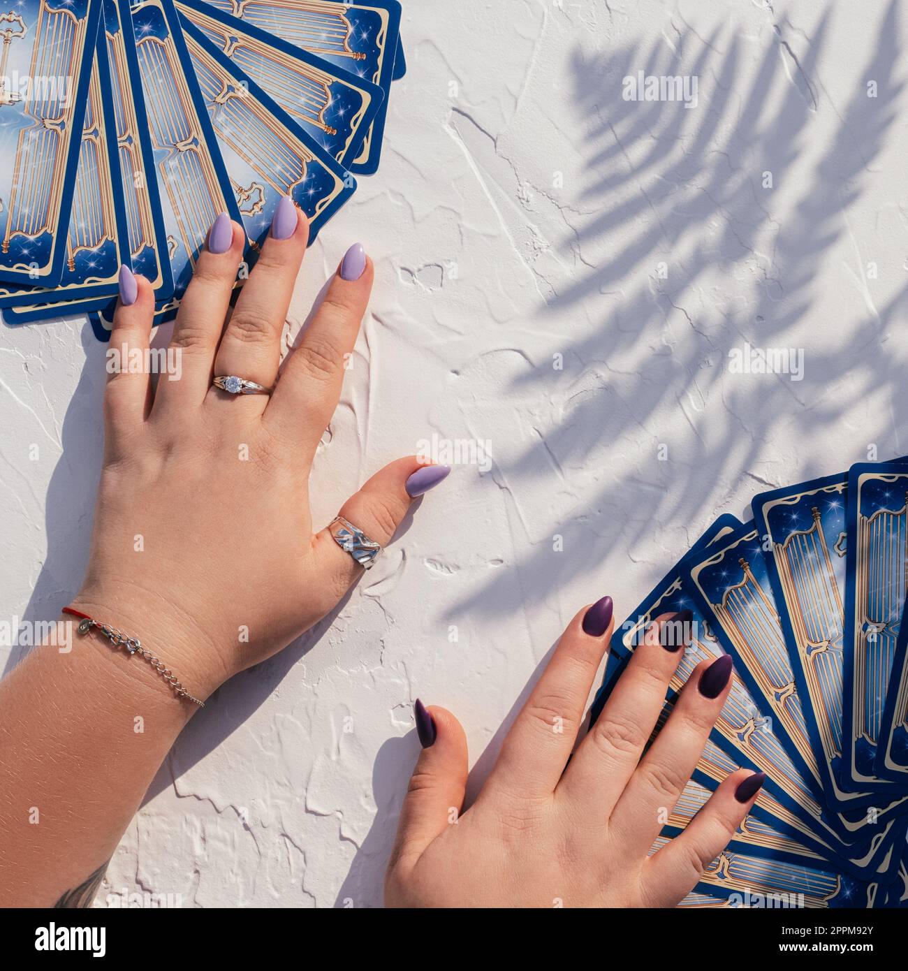 Hands with purple nails and rings on deck of Tarot cards fanned out on ...