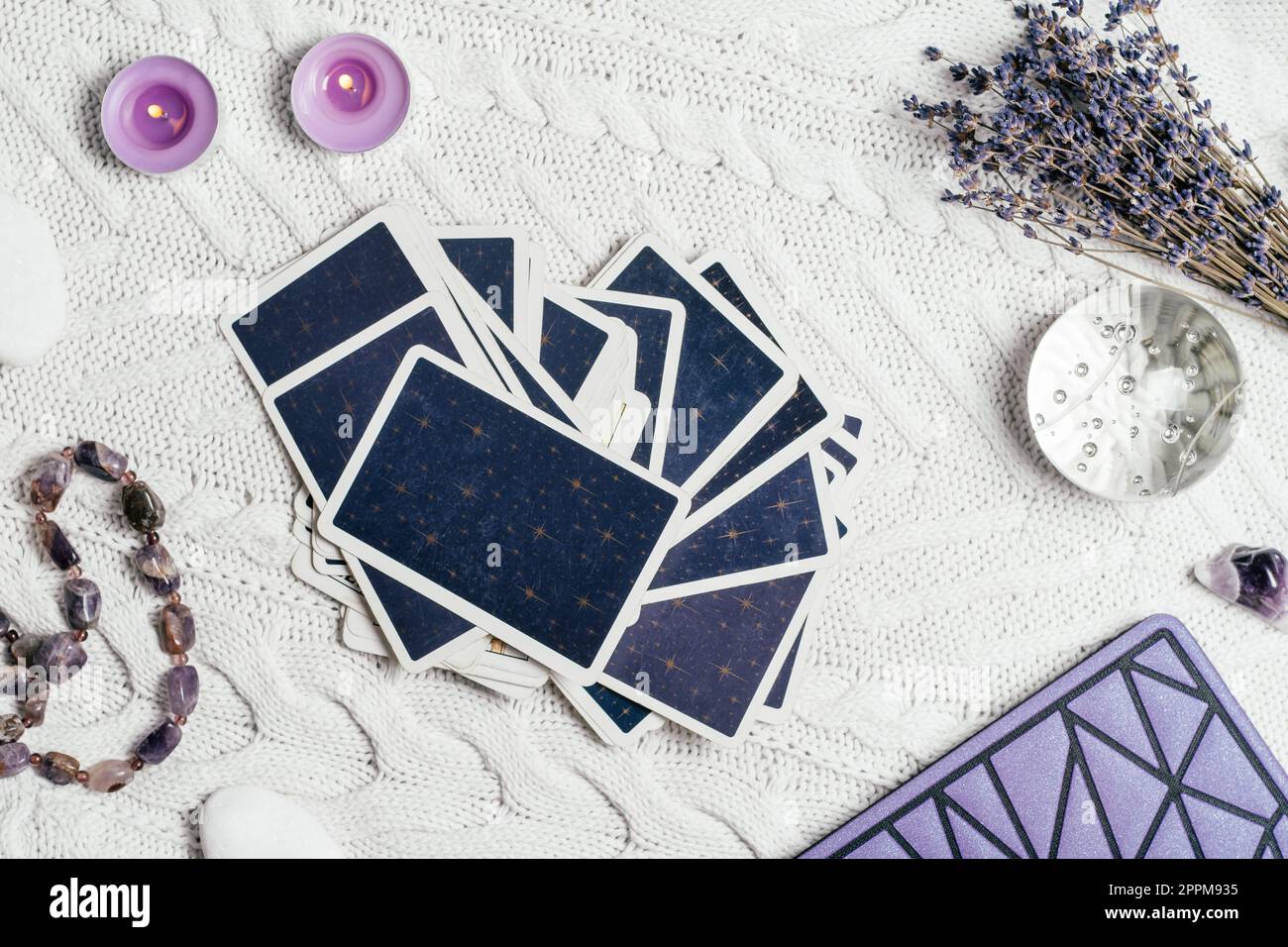 Tarot cards spread face up on white knitted surface with crystal ball ...