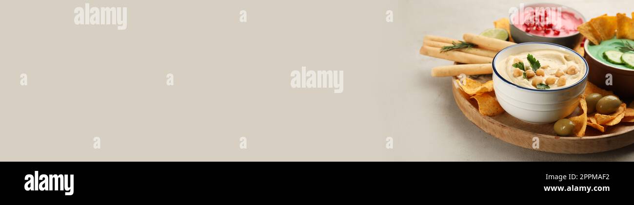Different delicious hummuses on light table, space for text. Banner ...