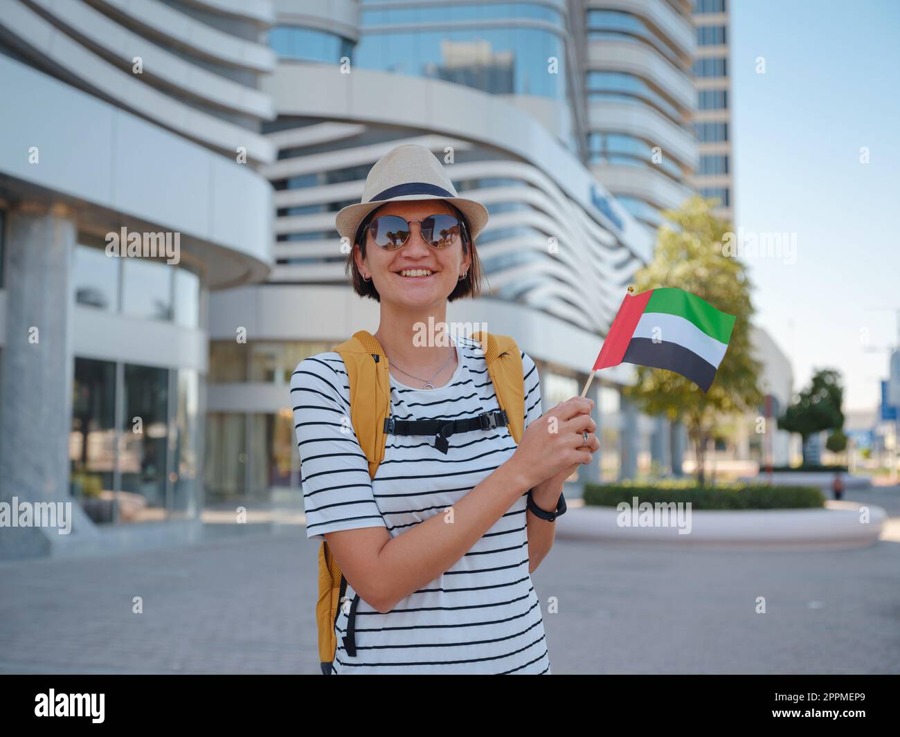 Happy young asian female traveler with backpack and hat with UAE flag ...