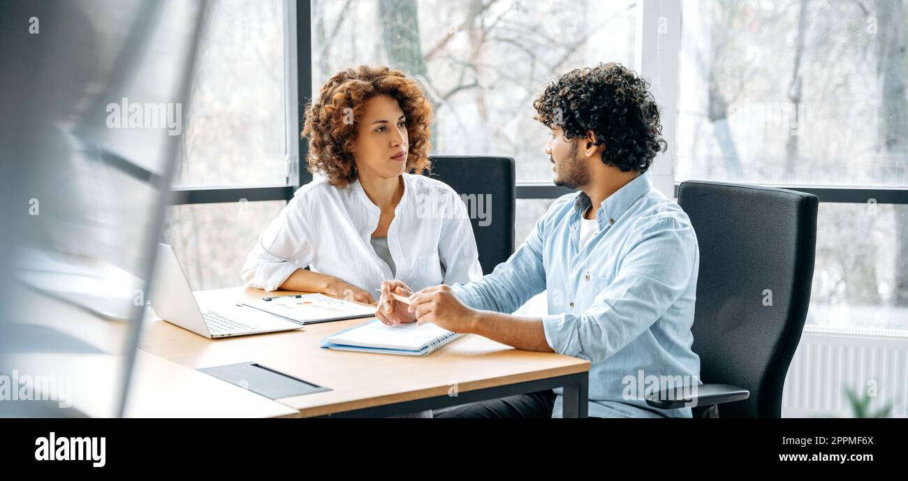 Panoramic photo of two focused employees of the company of different ...