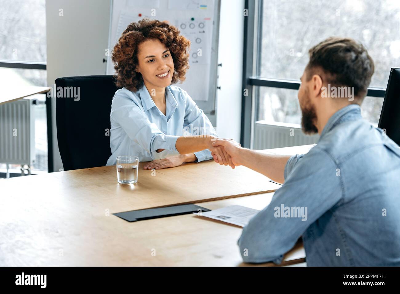Two people sitting at a desk in office, african american woman and ...