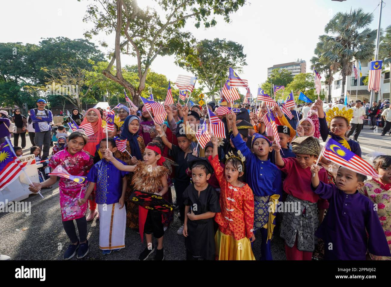 Group of children wear traditional costume raise the Malaysia flag ...