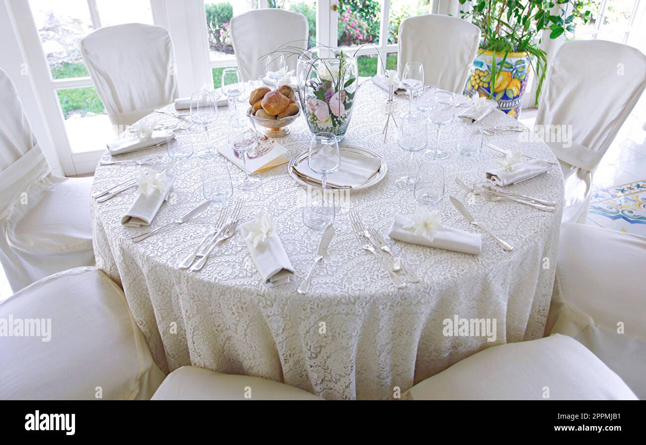 Bridal mise en place with white lace tablecloth and silver cutlery ...