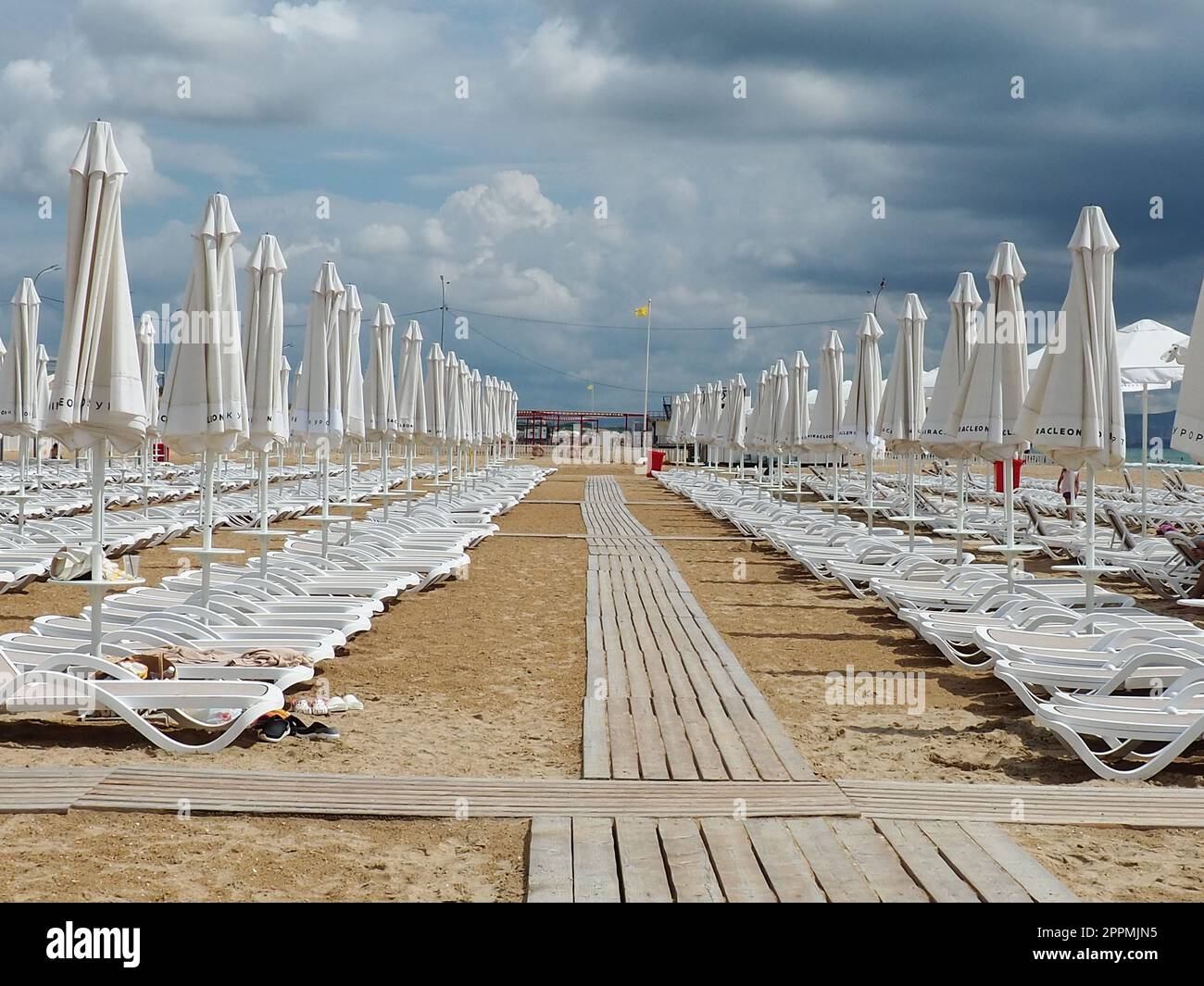 Wet sunbeds and umbrellas on the sea beach during heavy rain storm ...