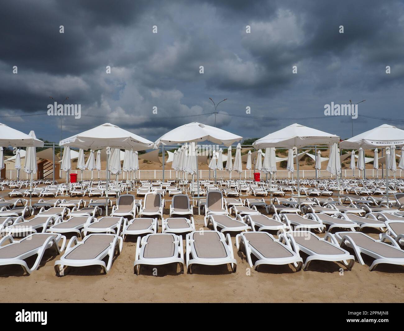 Wet sunbeds and umbrellas on the sea beach during heavy rain storm ...