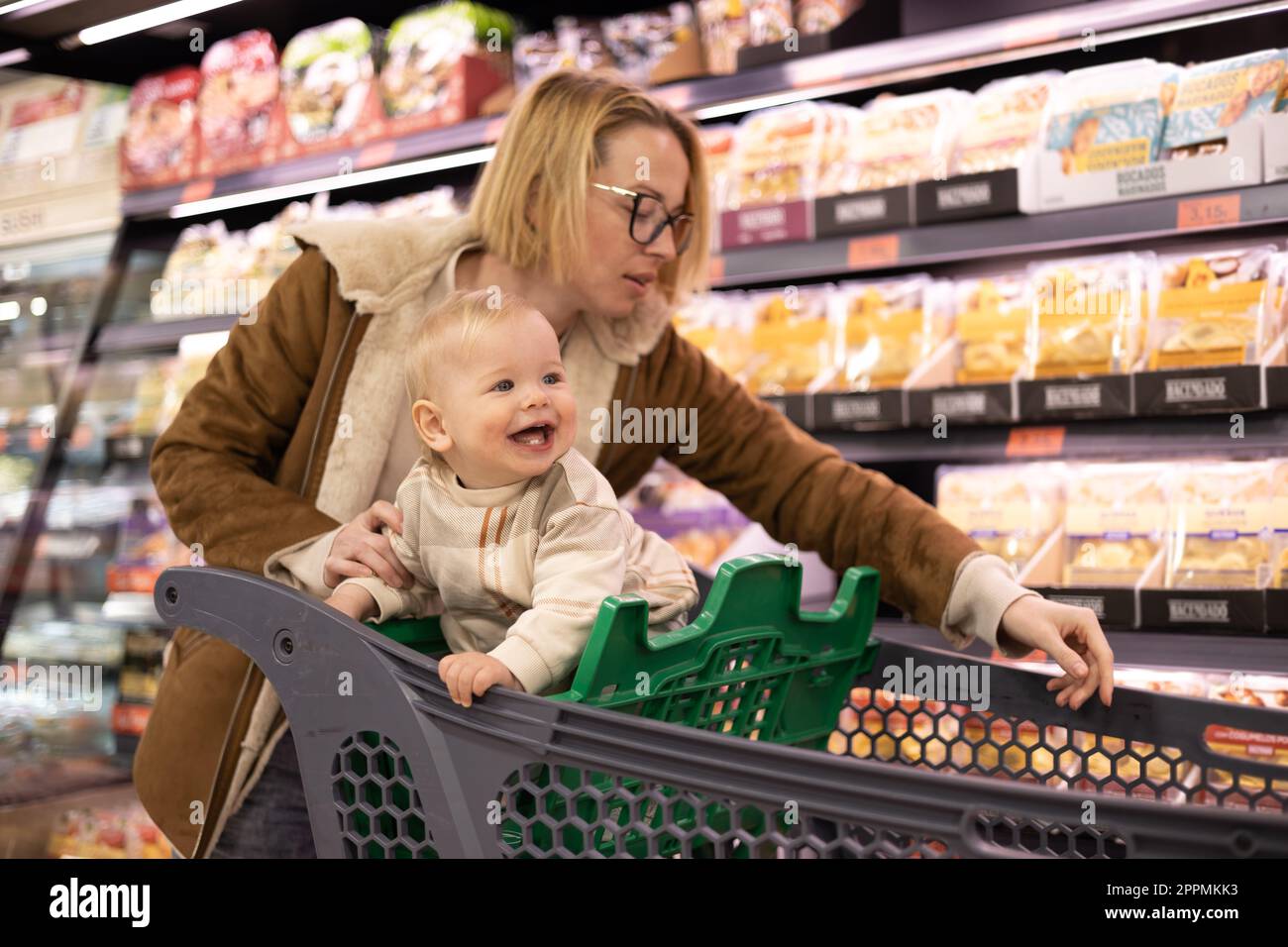 Caucasian mother shopping with her infant baby boy child choosing ...