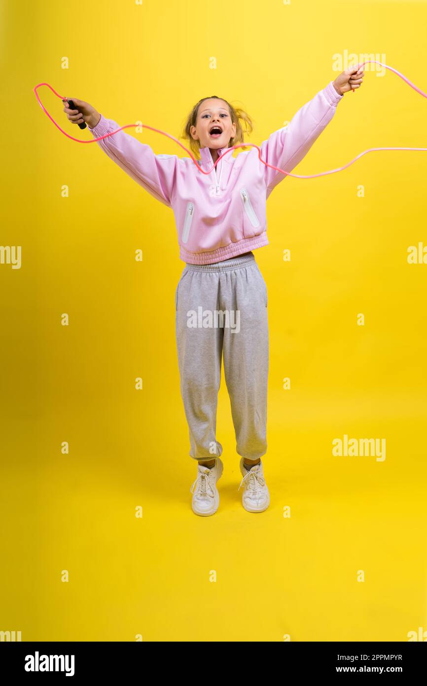 Adorable female child with skipping rope jumping in studio Stock Photo ...