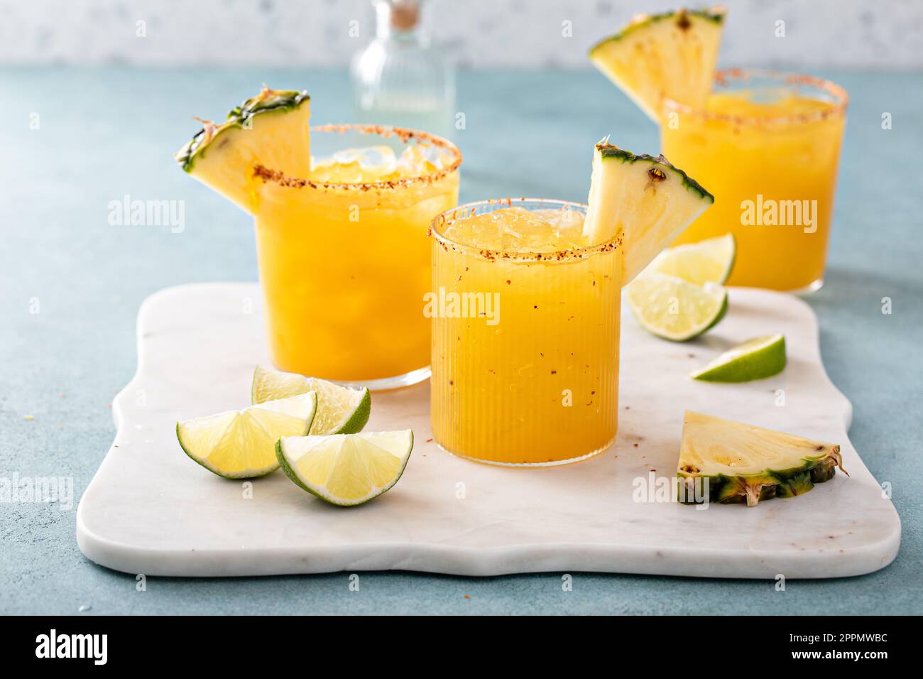 Pineapple margarita cocktail in glasses with chili tajin rim and a ...