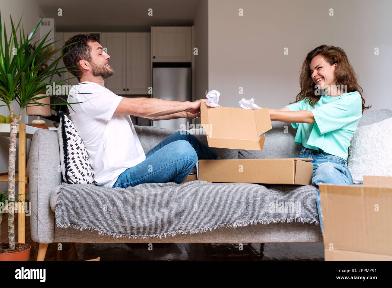 Man and woman have fun at home each pulling a box of online purchase ...