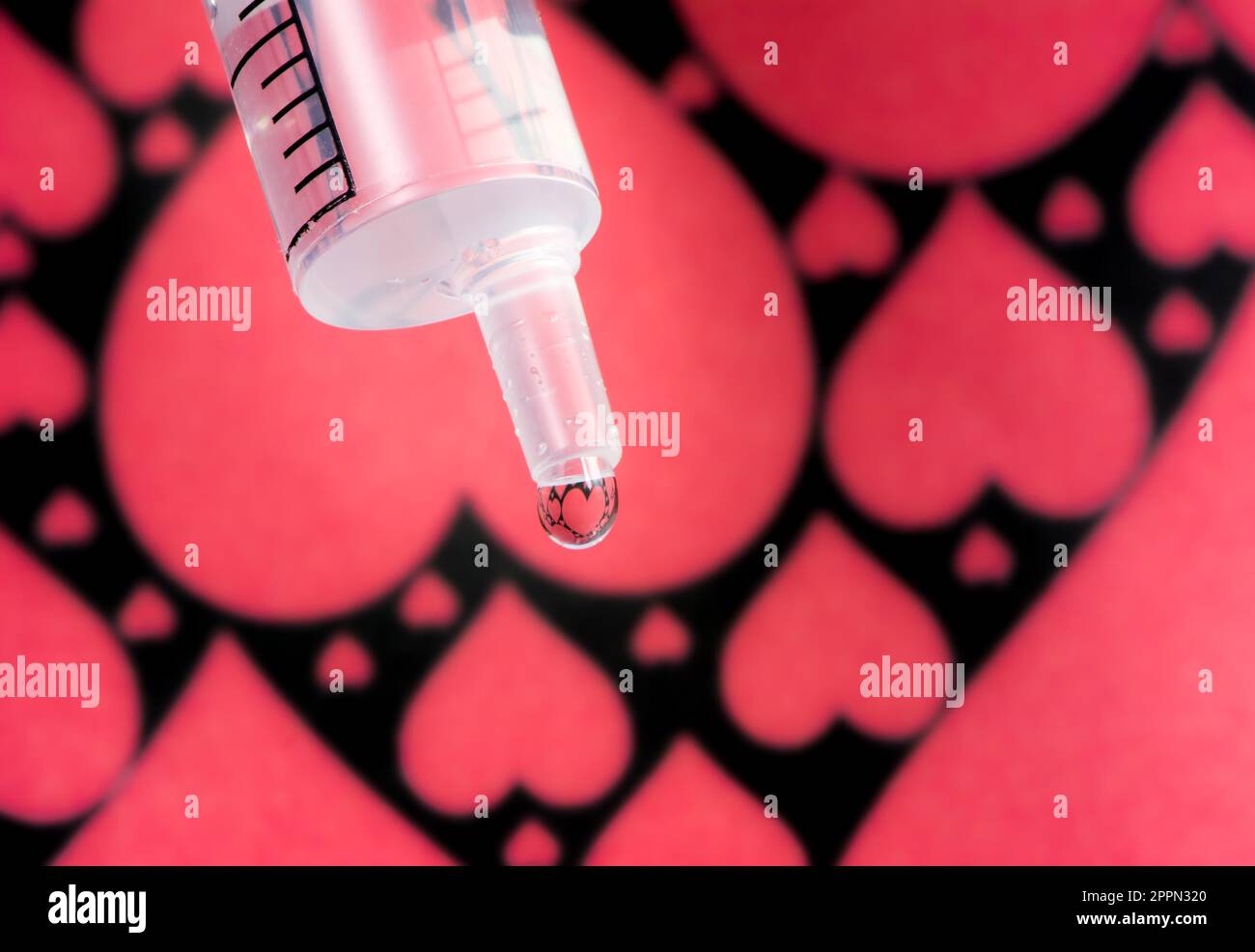 Love injection concept with a syringe an a heart refracting in a drop ...