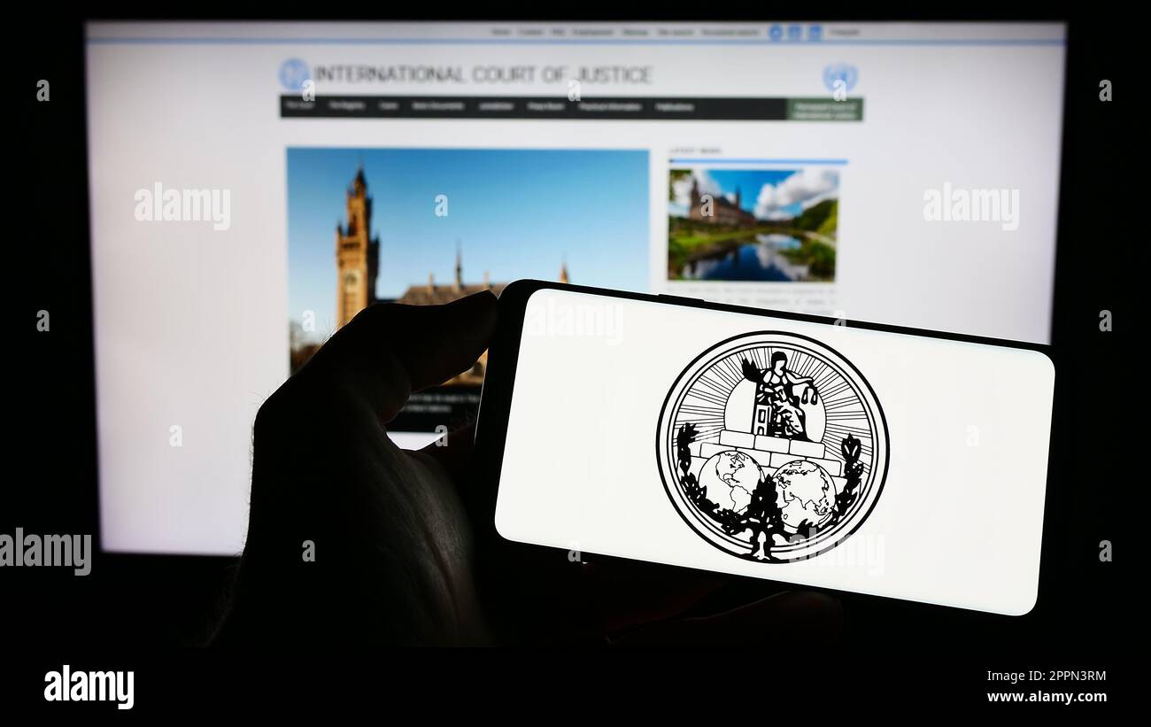 Person holding mobile phone with logo of the International Court of ...