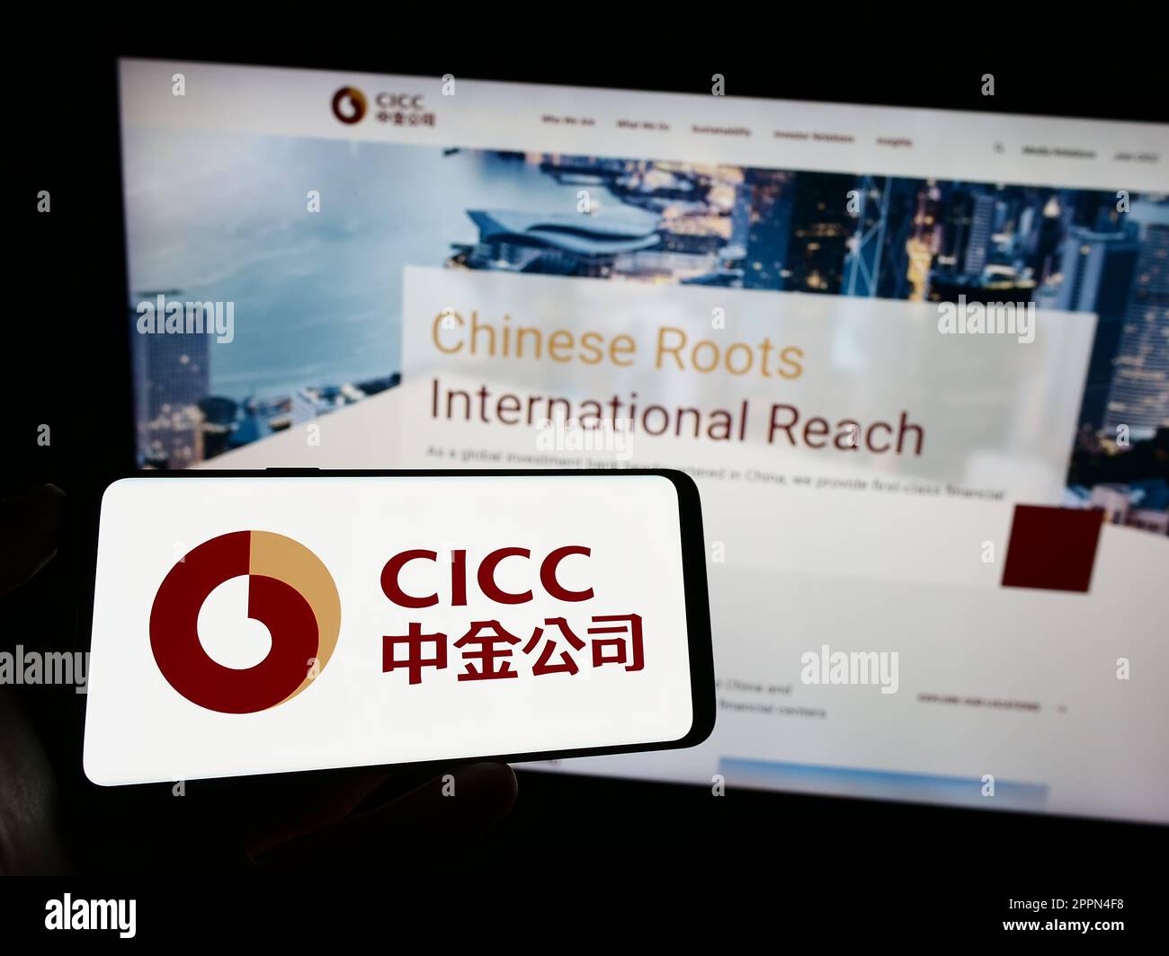 Person holding mobile phone with logo of China International Capital ...