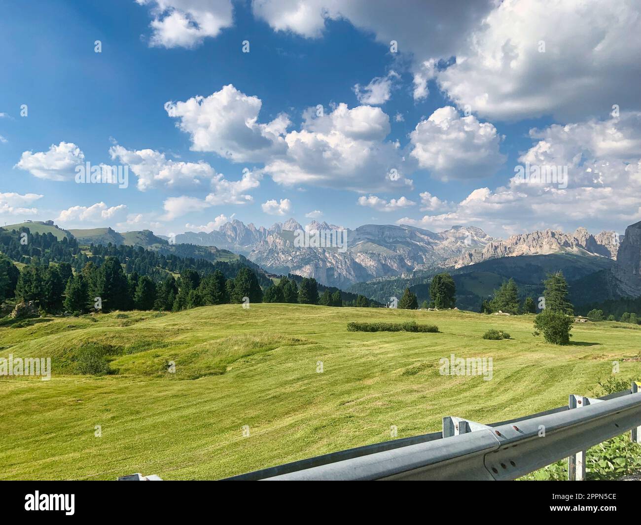 A scenic view of a highway lined by trees winding between two mountain ...
