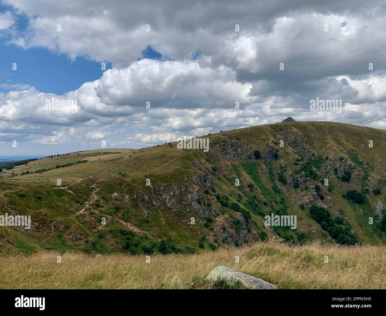 A rugged stone outcrop standing atop a rolling grassy hill Stock Photo ...