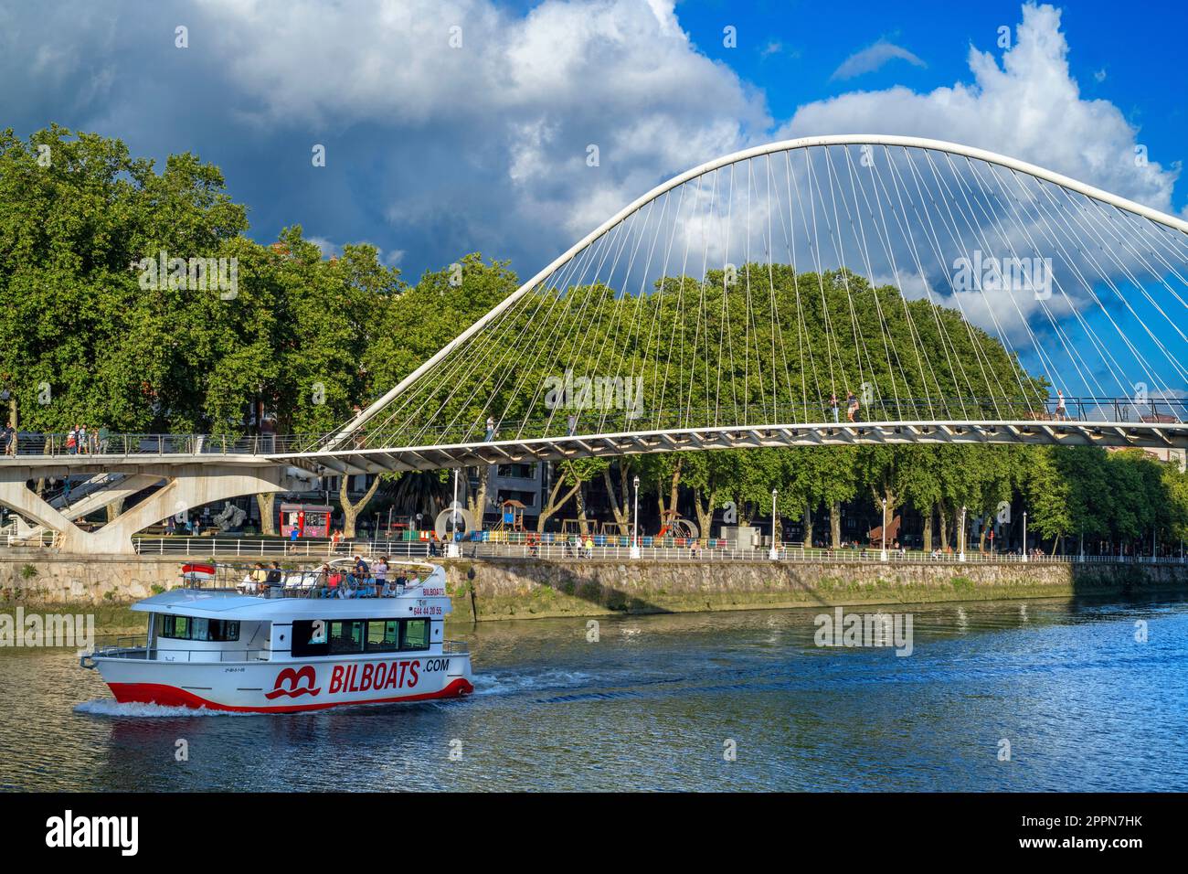 Bilbao river cruise boat on the Nervion river passing the Zubizuri ...