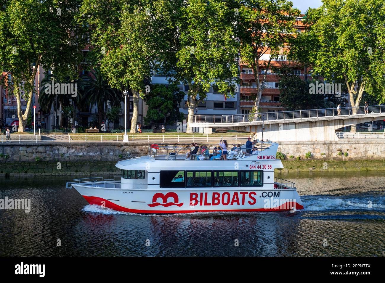 Bilbao river cruise boat on the Nervion river passing the Zubizuri ...