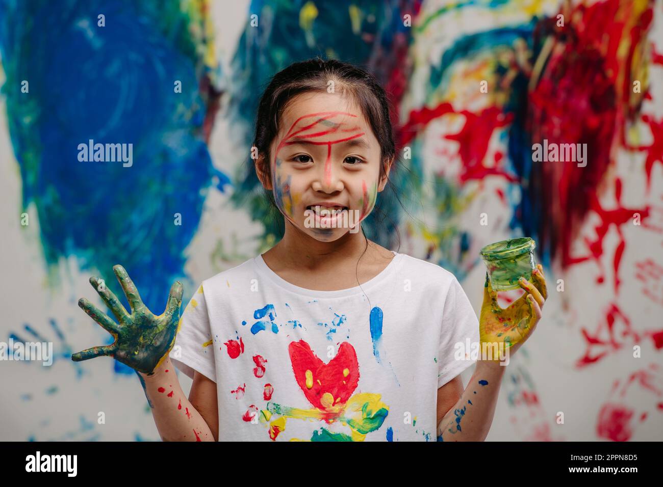 Portrait of happy kid with finger colours and painted t-shirts, studio ...