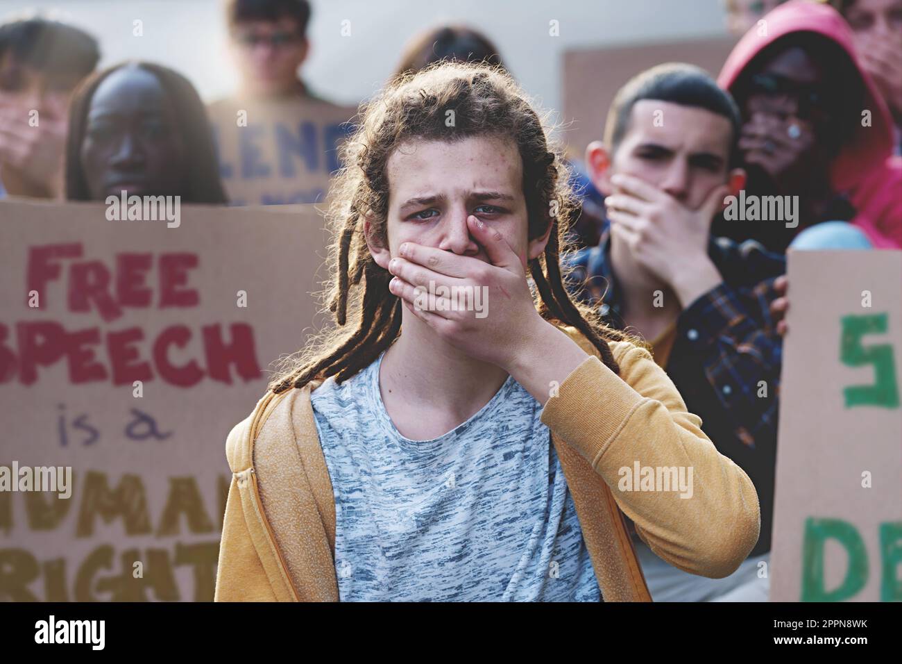 Group of students protesting outdoors, covering their mouths and ...