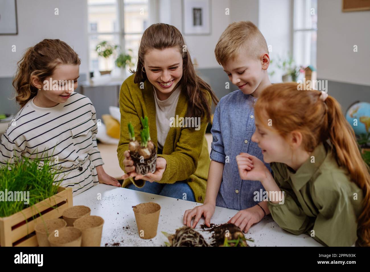 Young teacher learning pupils how to take care about plants Stock Photo ...