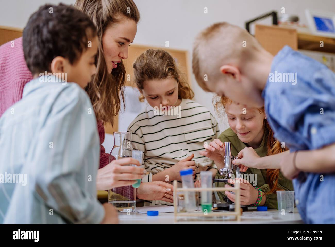 Young teacher doing chemistry experiment with pupils during science ...