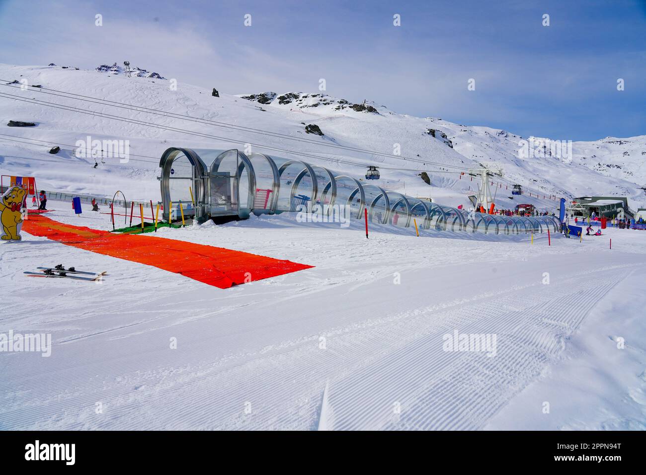 Tapis roulant dans un tunnel de verre sur la piste de ski d'une école ...