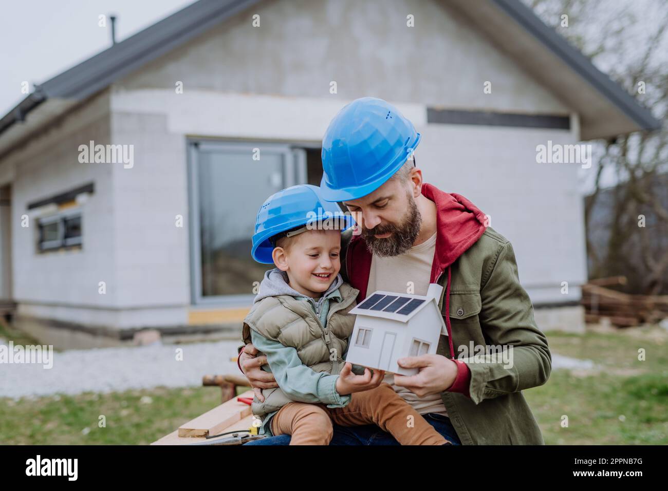 Father and his little son in front of their unfinished house holding ...