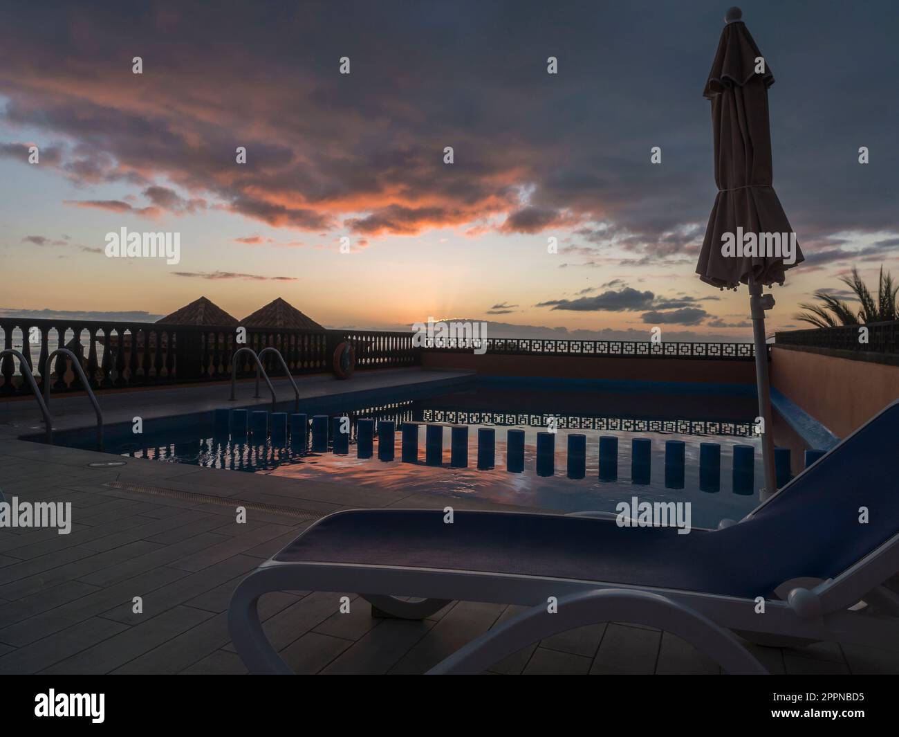 View of a sun bed and umbrella at pool area on rooftop of apartment in Valle Gran Rey during red ...