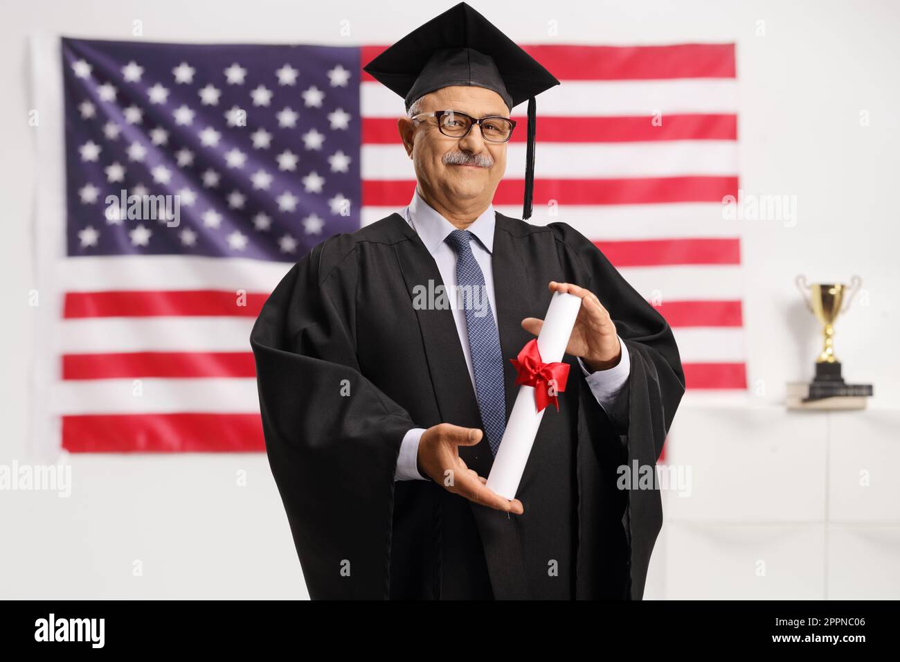 University dean in a graduation gown holding a diploma with the USA ...