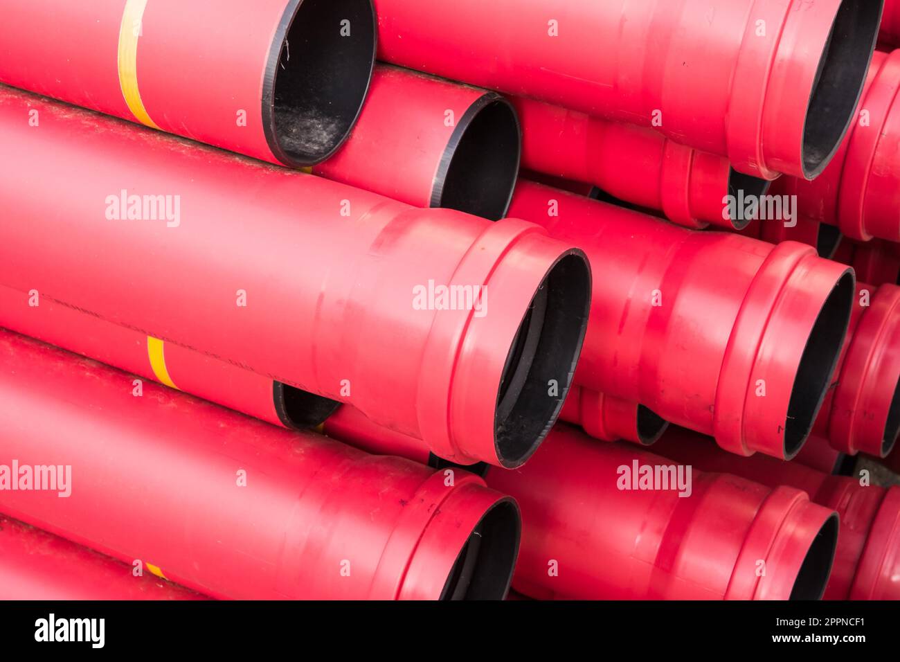 Pile of red pvc protective pipes Stock Photo - Alamy