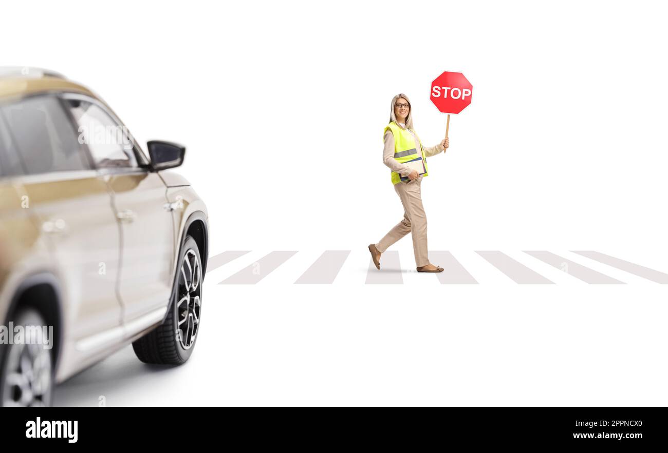 Car driving towards a woman at a pedestrian crossing carrying a stop ...