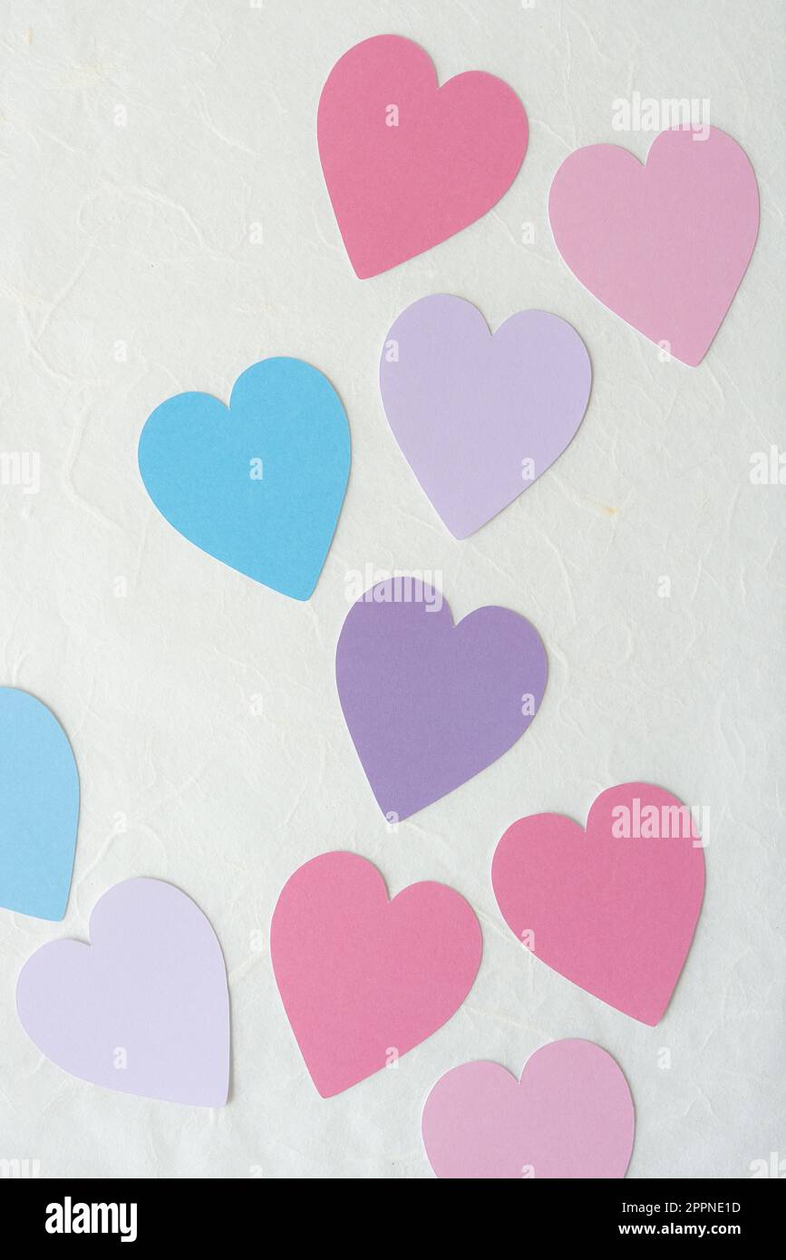 set of variously coloured paper hearts on a light paper background ...
