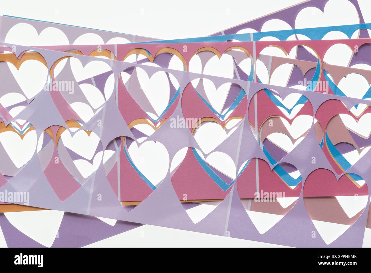 variously coloured paper stencils with machine cut hearts on a white ...