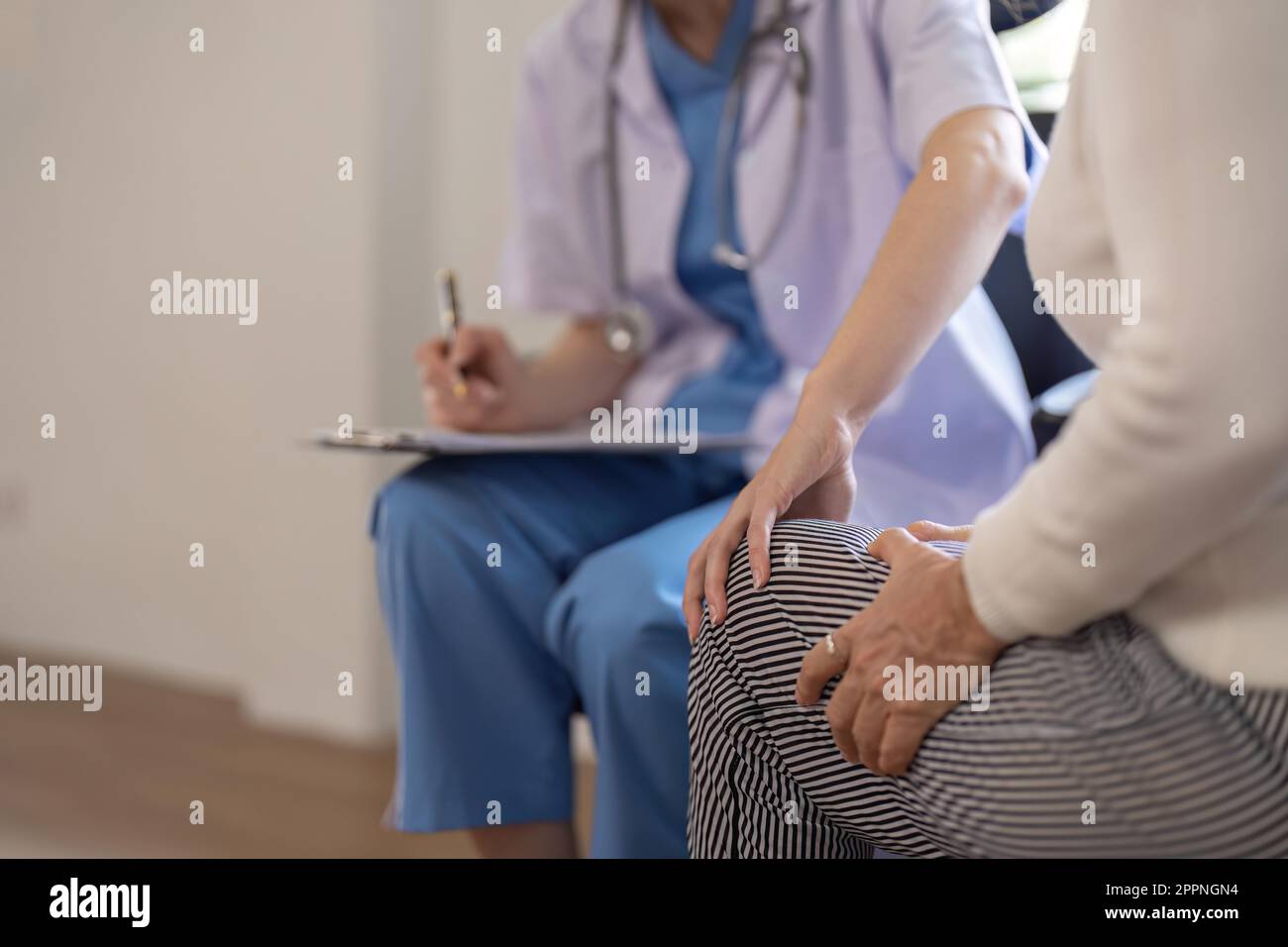 Doctor woman holding knee and looking at aged woman patient while ...