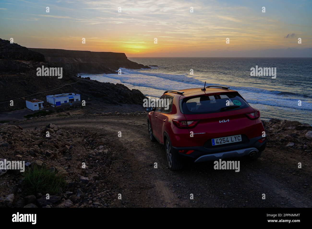 Red car on a dirt road descending towards Puertito de los Molinos, a ...