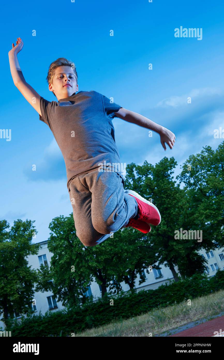 Full body low angle oblique view of teenage boy jumping in the air with ...