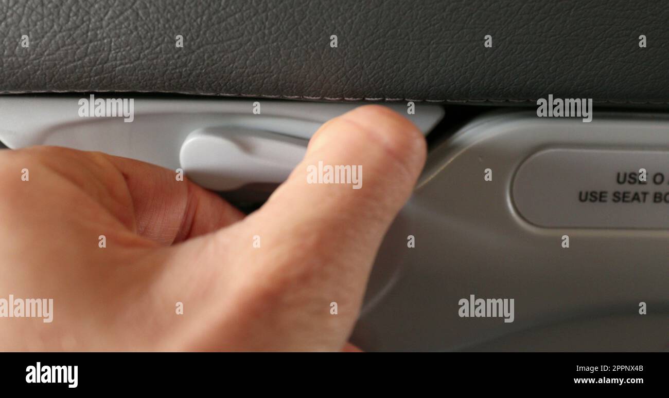 Airplane tray table lock. Closeup of passenger hand opening and closing ... Airplane tray table lock. Closeup of passenger hand opening and closing ...