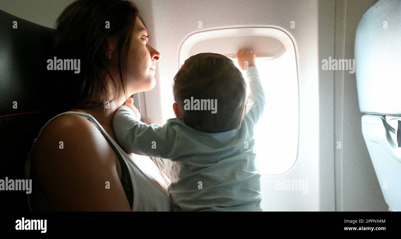 Baby reaching out to plane window. Mother traveling with infant son ...