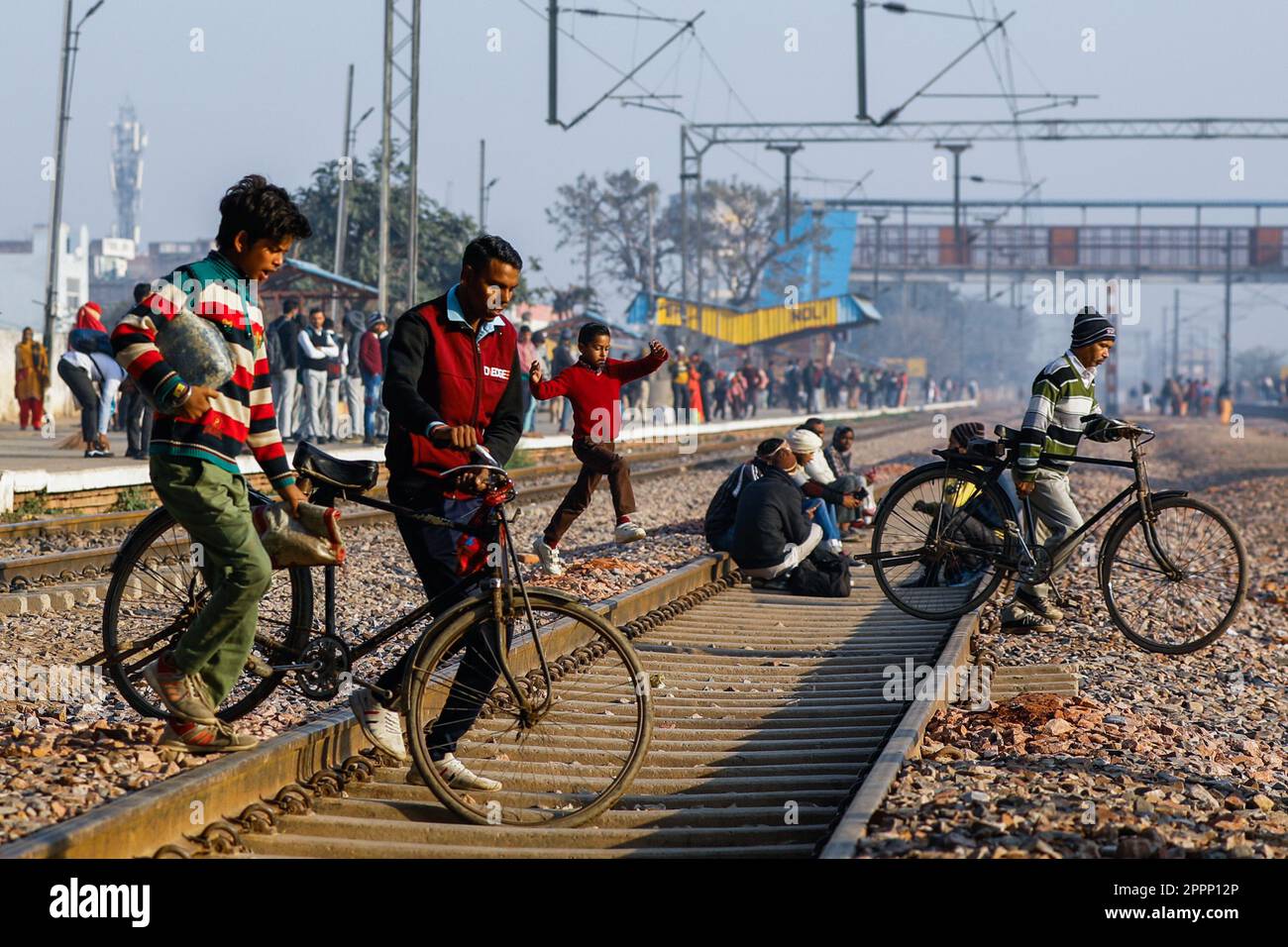 Indian commuters walk past a railway track at a Noli railway station in ...