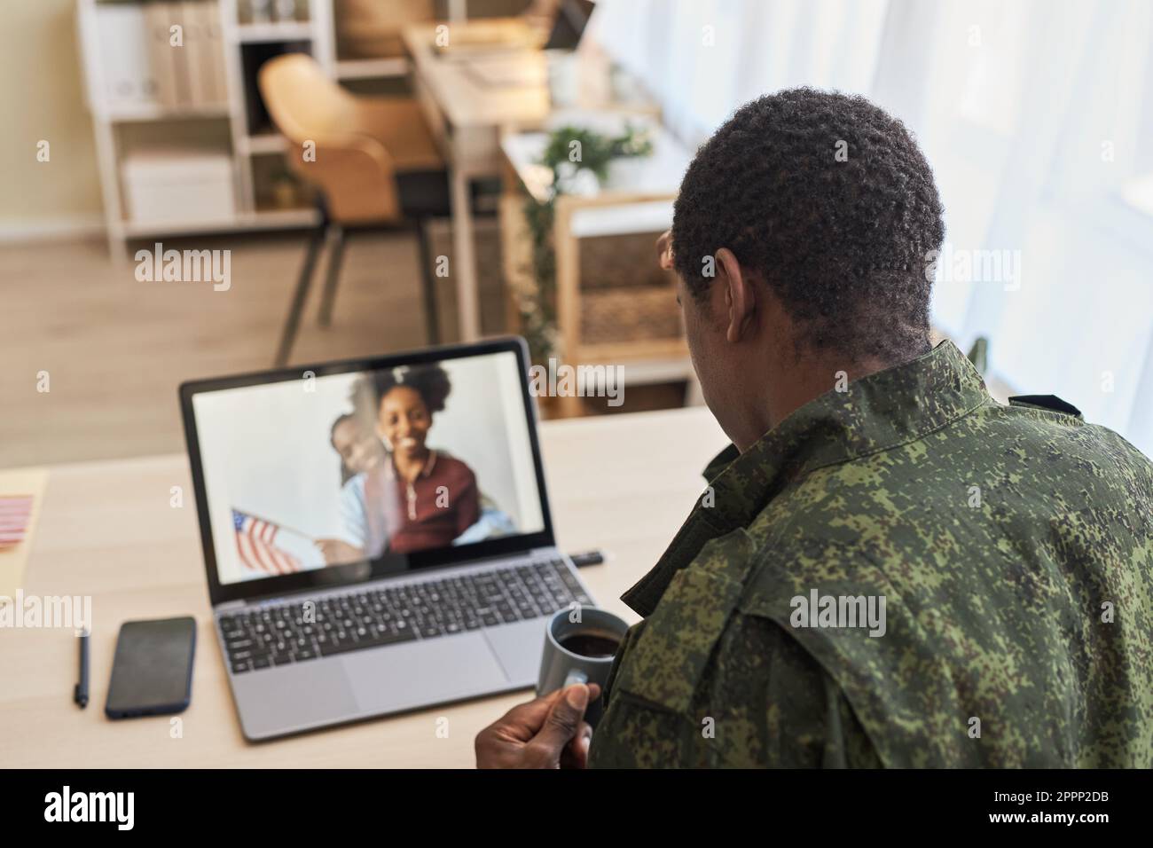 Rear view of military dad talking to his family online on laptop during ...