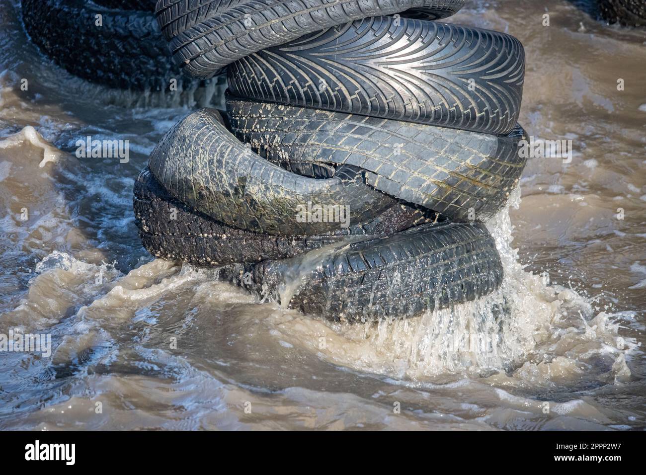 Water waves crash into a coastal barrier made of old tires Stock Photo ...
