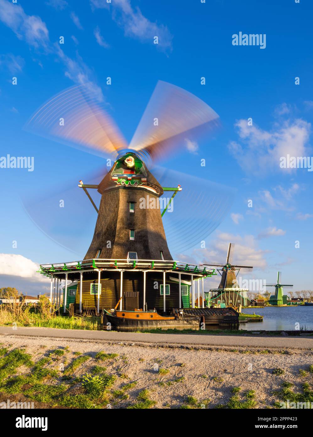 A traditional Dutch windmill spins in the rural landscape of Zaanse ...
