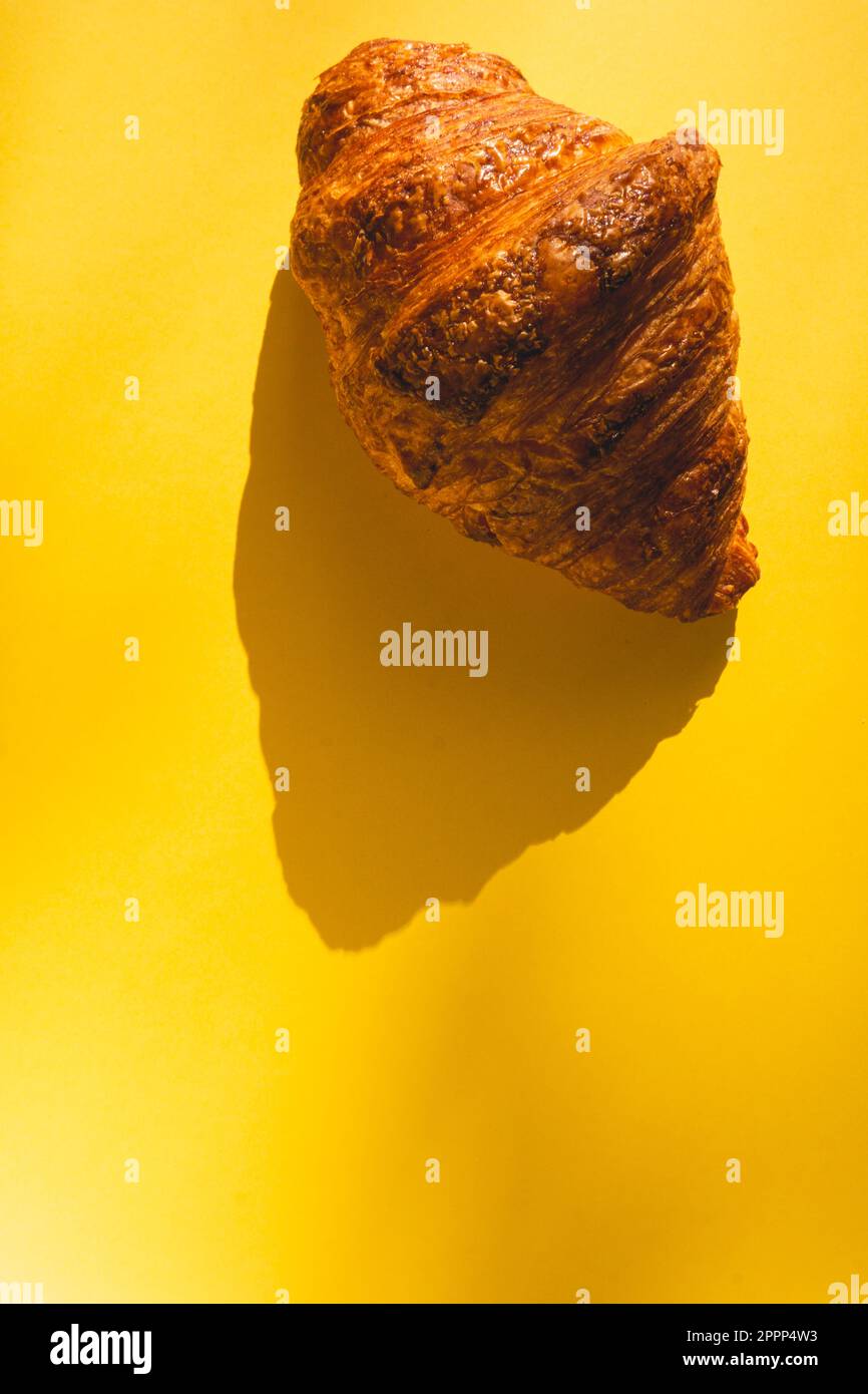 High angle view of a freshly baked croissant on yellow background with ...