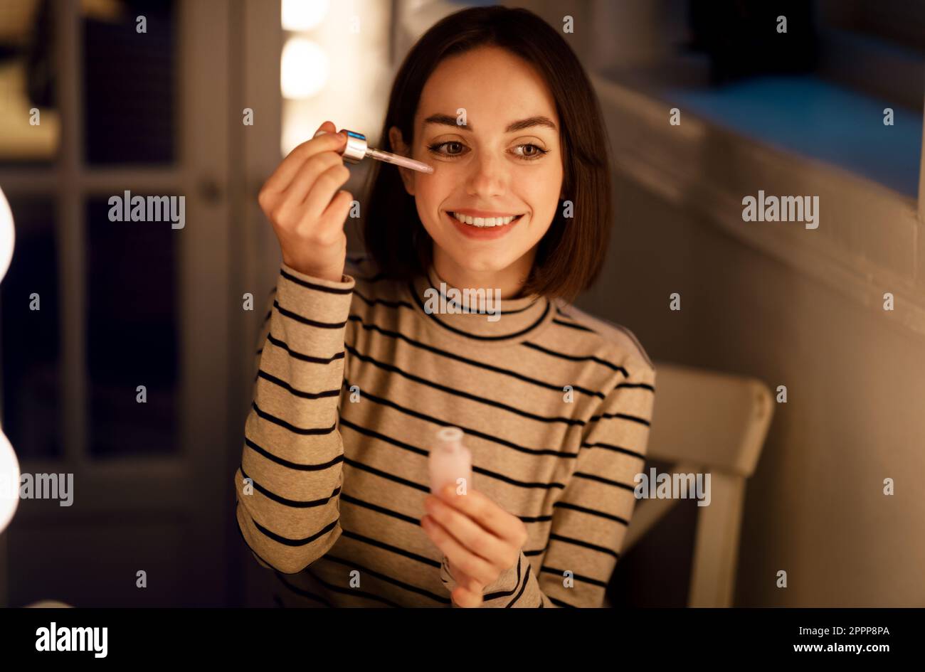 Smiling young brunette woman doing face care routine at home Stock ...
